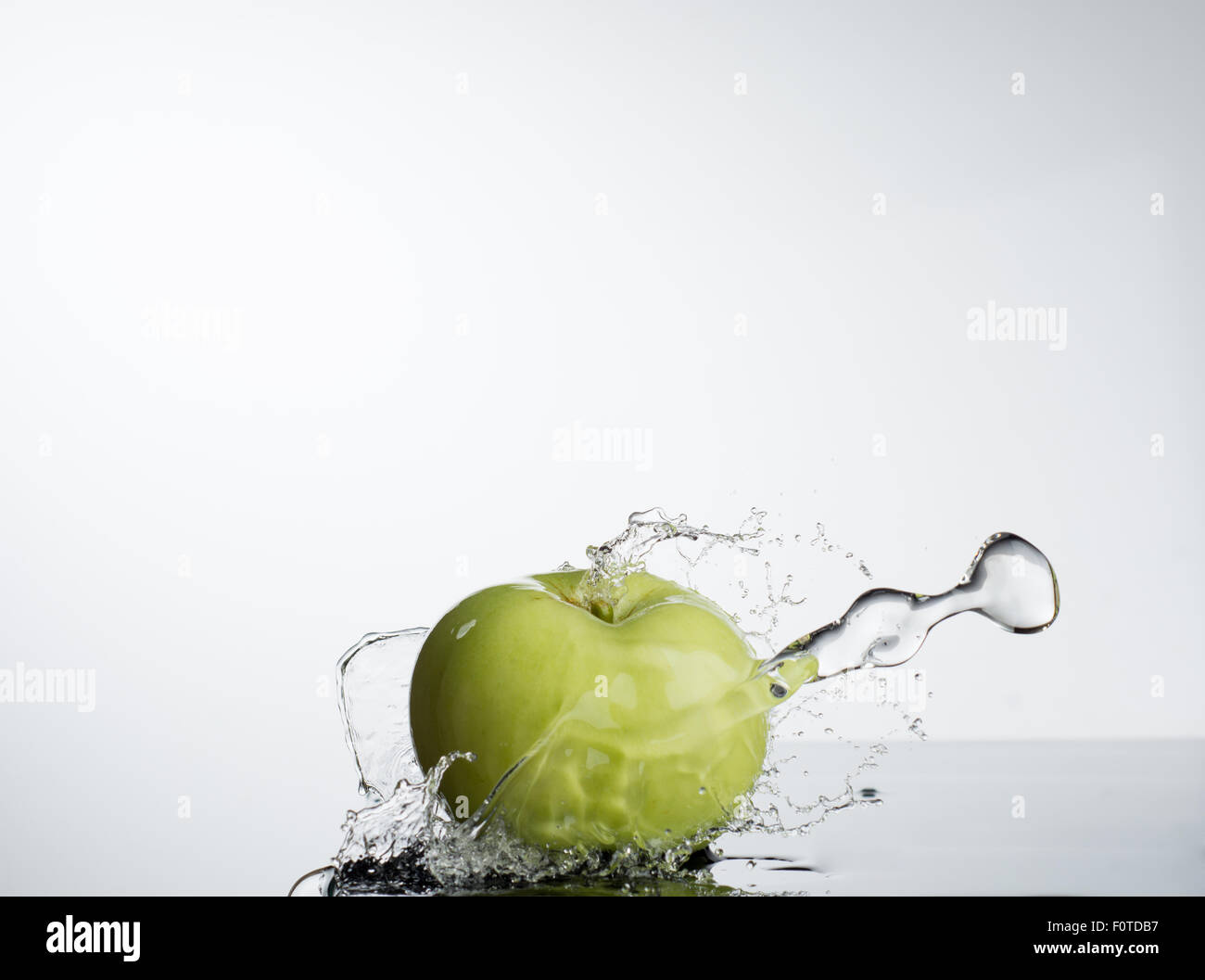 Green apple in splash of water on white background Stock Photo - Alamy