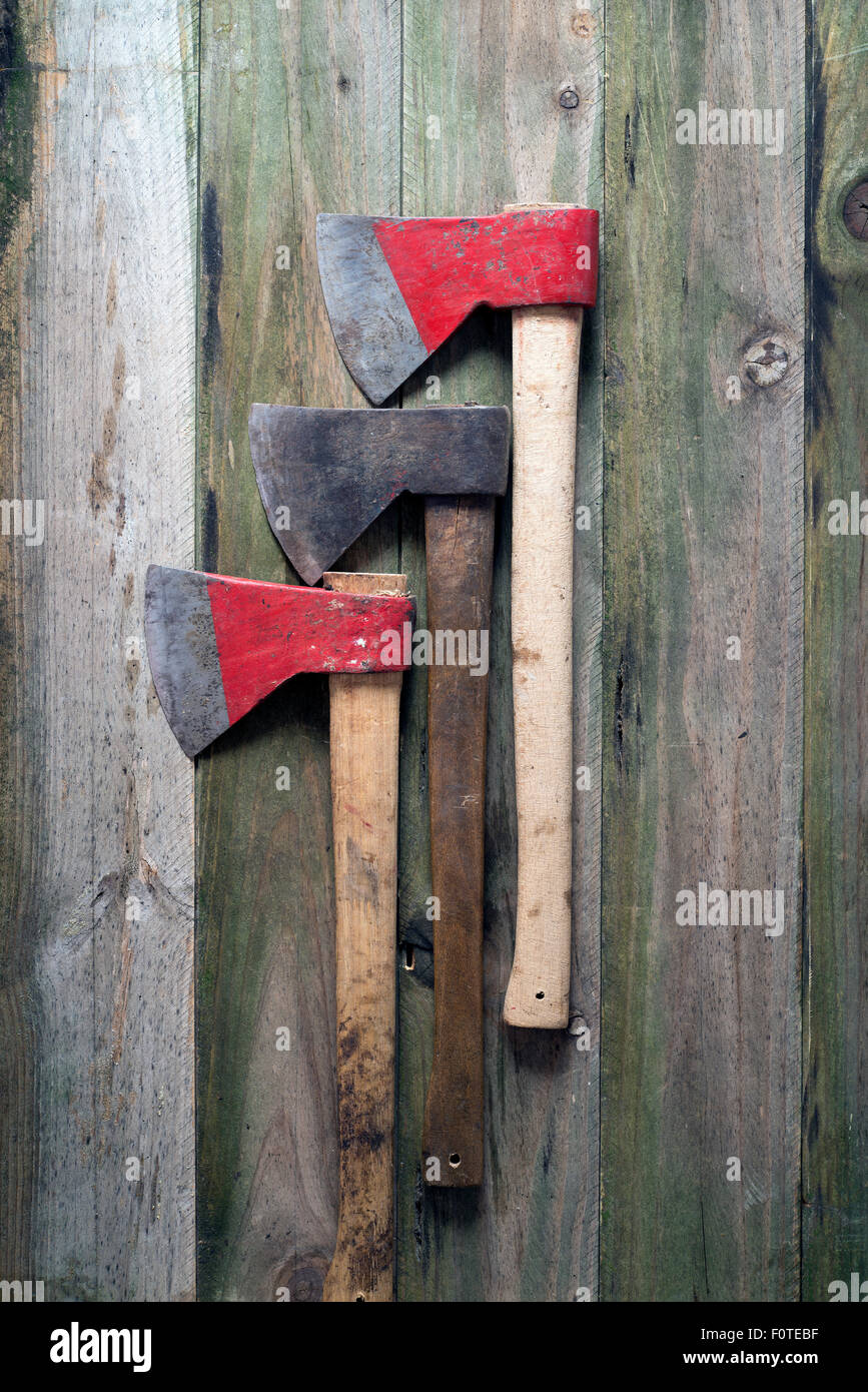 Three axes on a wooden background Stock Photo - Alamy