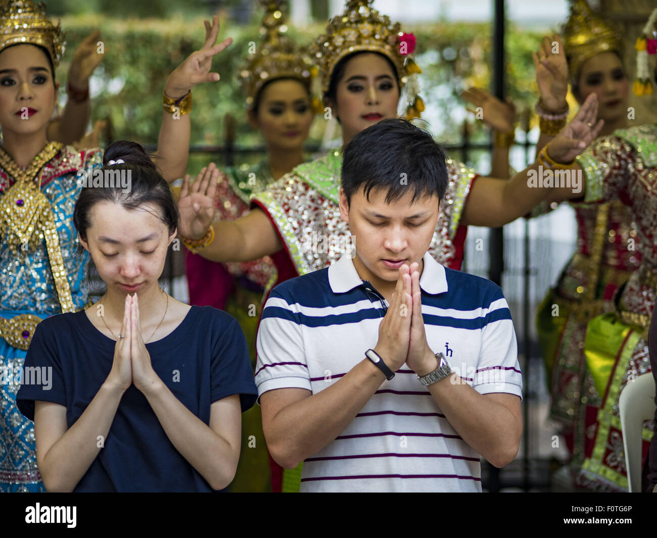 Bangkok, Thailand. 21st Aug, 2015. People pray as Thai dancers perform ...