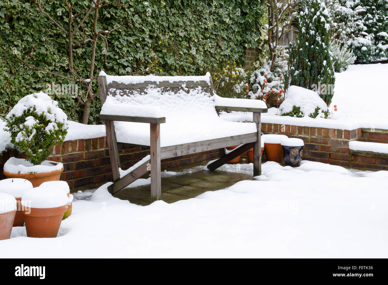 Snow covered garden bench on a patio in winter Stock Photo - Alamy