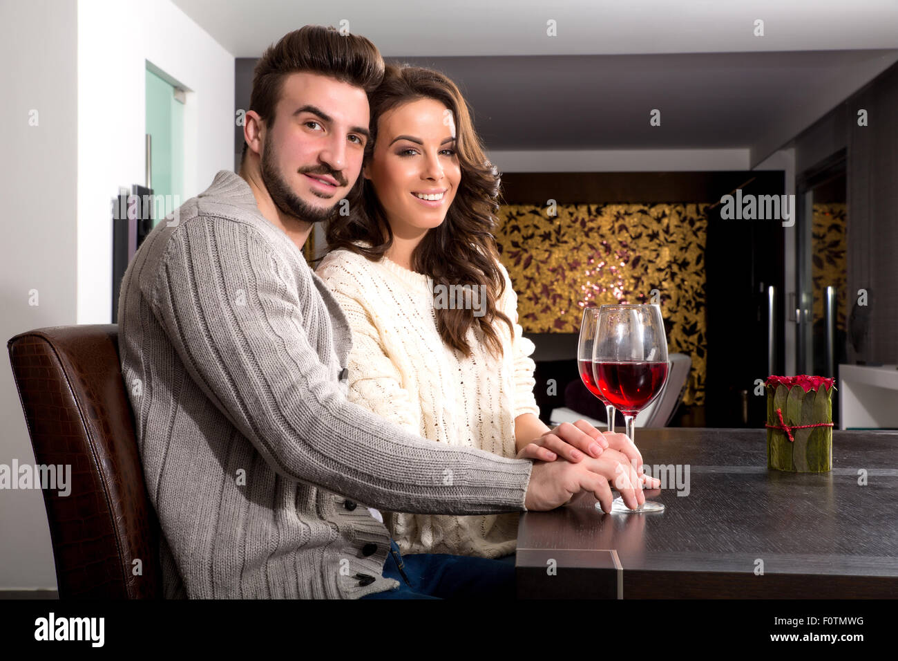 A young couple enjoying a glass of wine at night time at home Stock ...