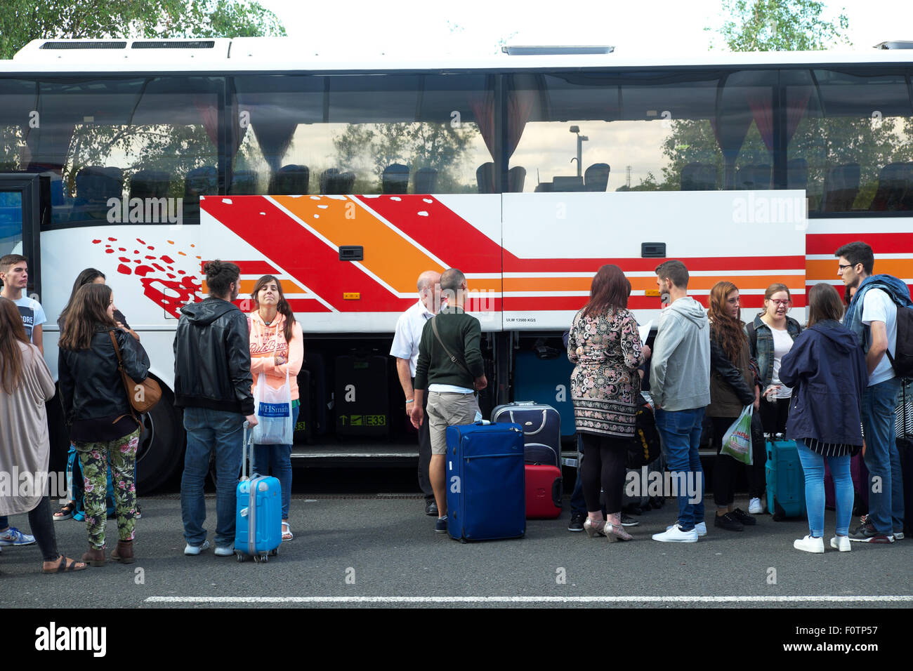 Coach travel passengers queue to load their baggage onto a coach ...