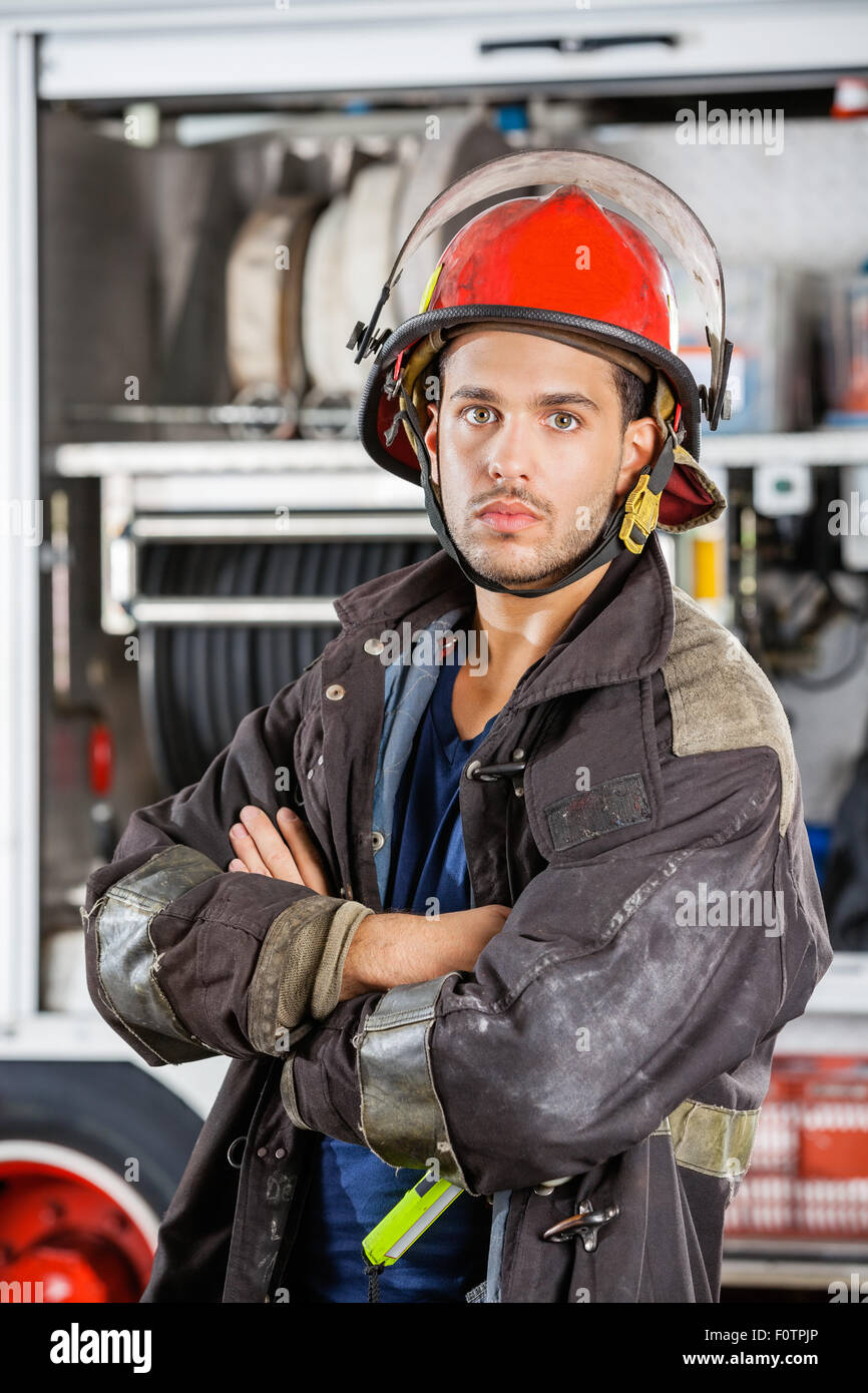 Portrait of confident firefighter standing arms crossed against ...