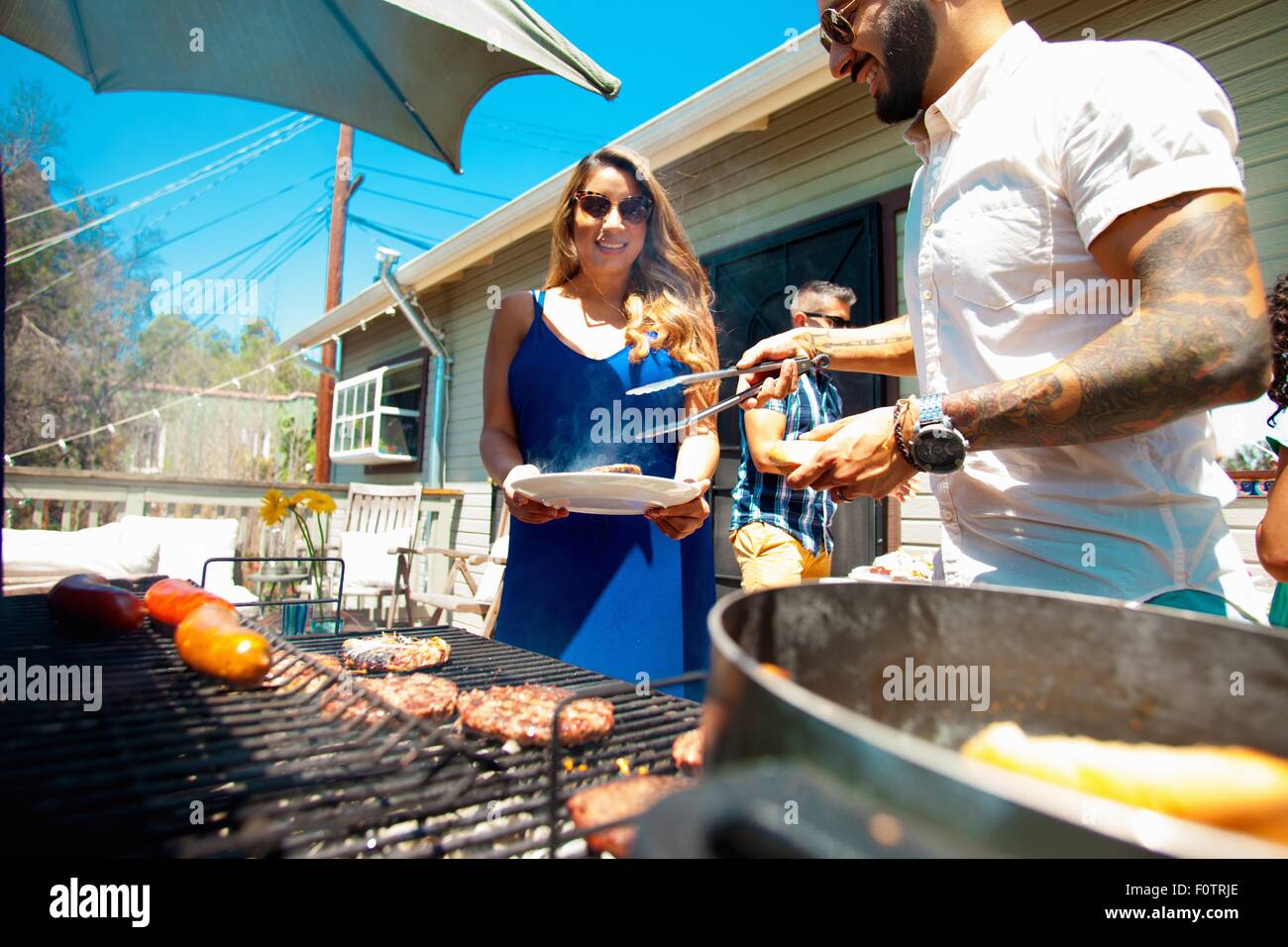 Mid adult man serving barbecue food to family in garden Stock Photo - Alamy