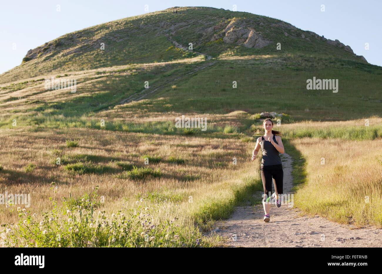 Young woman running on hillside track Stock Photo - Alamy