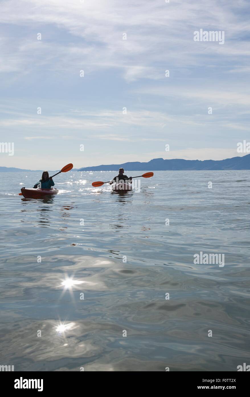 Kayakers sitting in kayaks on water infront of mountain range, Great ...