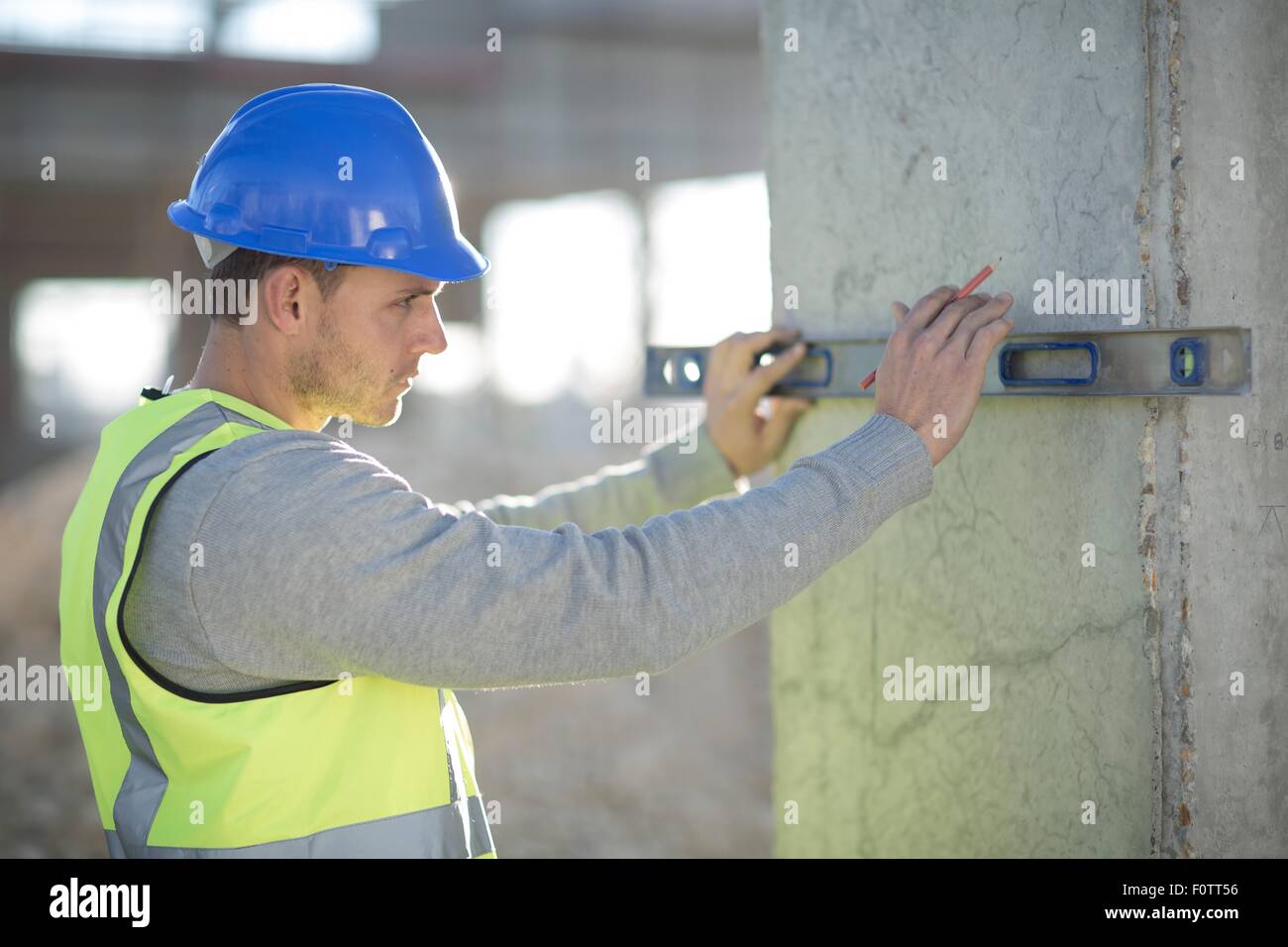 Surveyor using spirit level on construction site pillar Stock Photo - Alamy