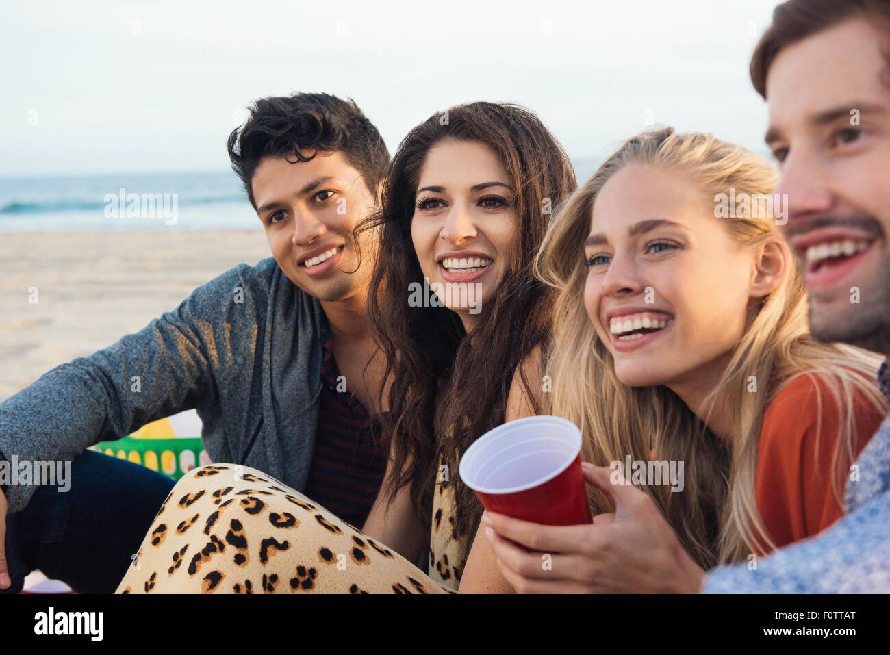 Group of friends sitting together on beach Stock Photo - Alamy
