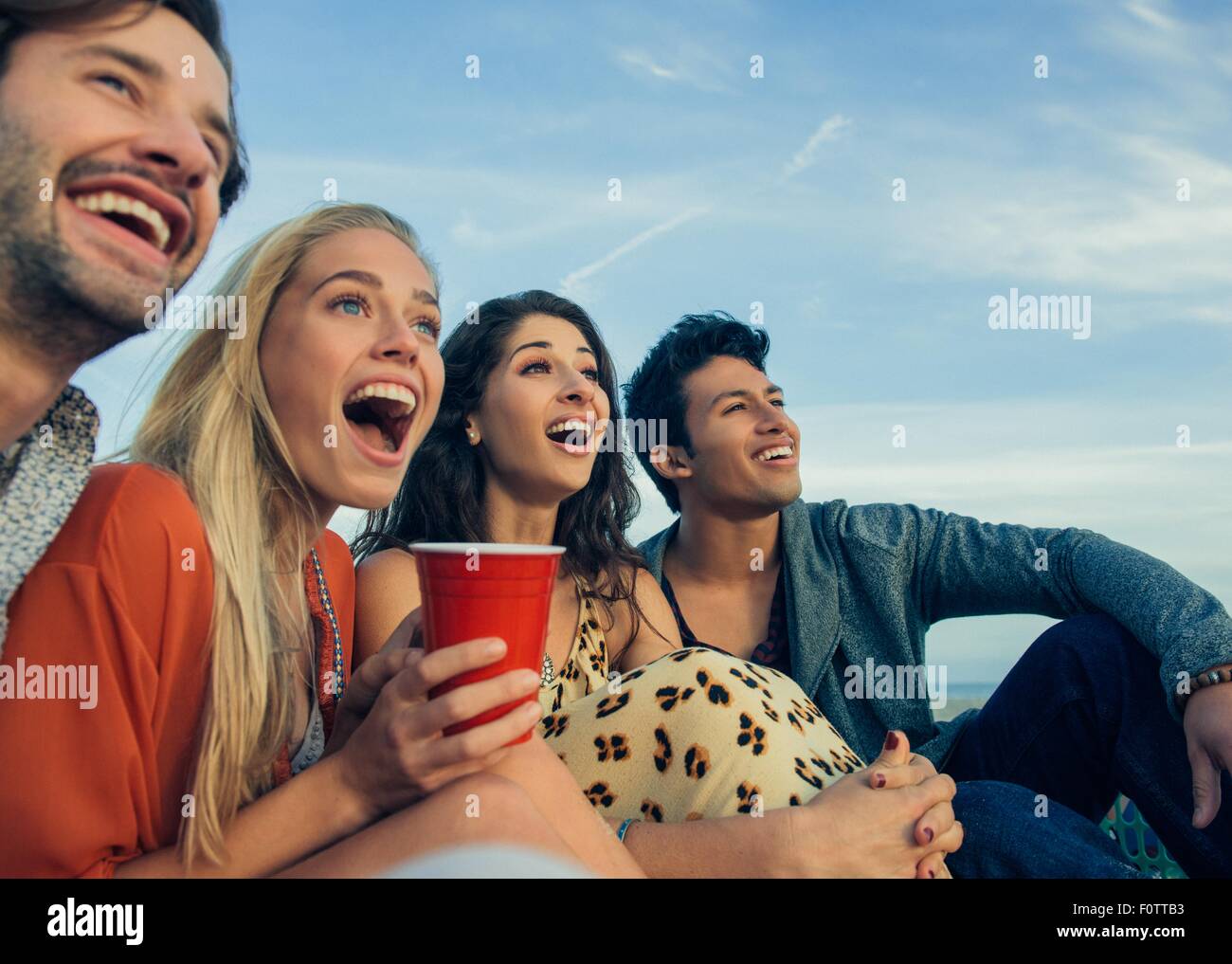 Group of friends sitting together outdoors, laughing Stock Photo - Alamy