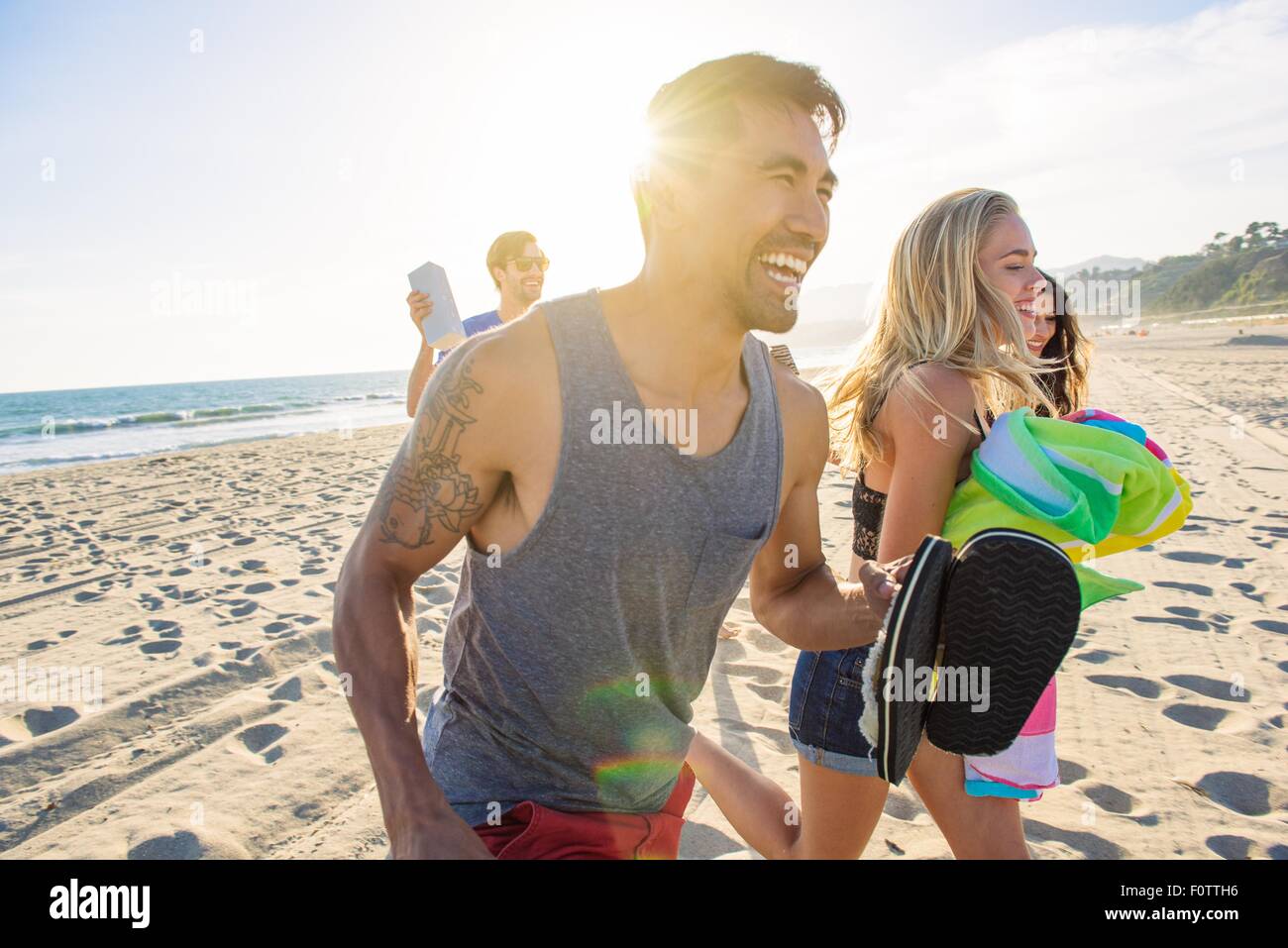 Group of friends walking on beach, laughing Stock Photo - Alamy