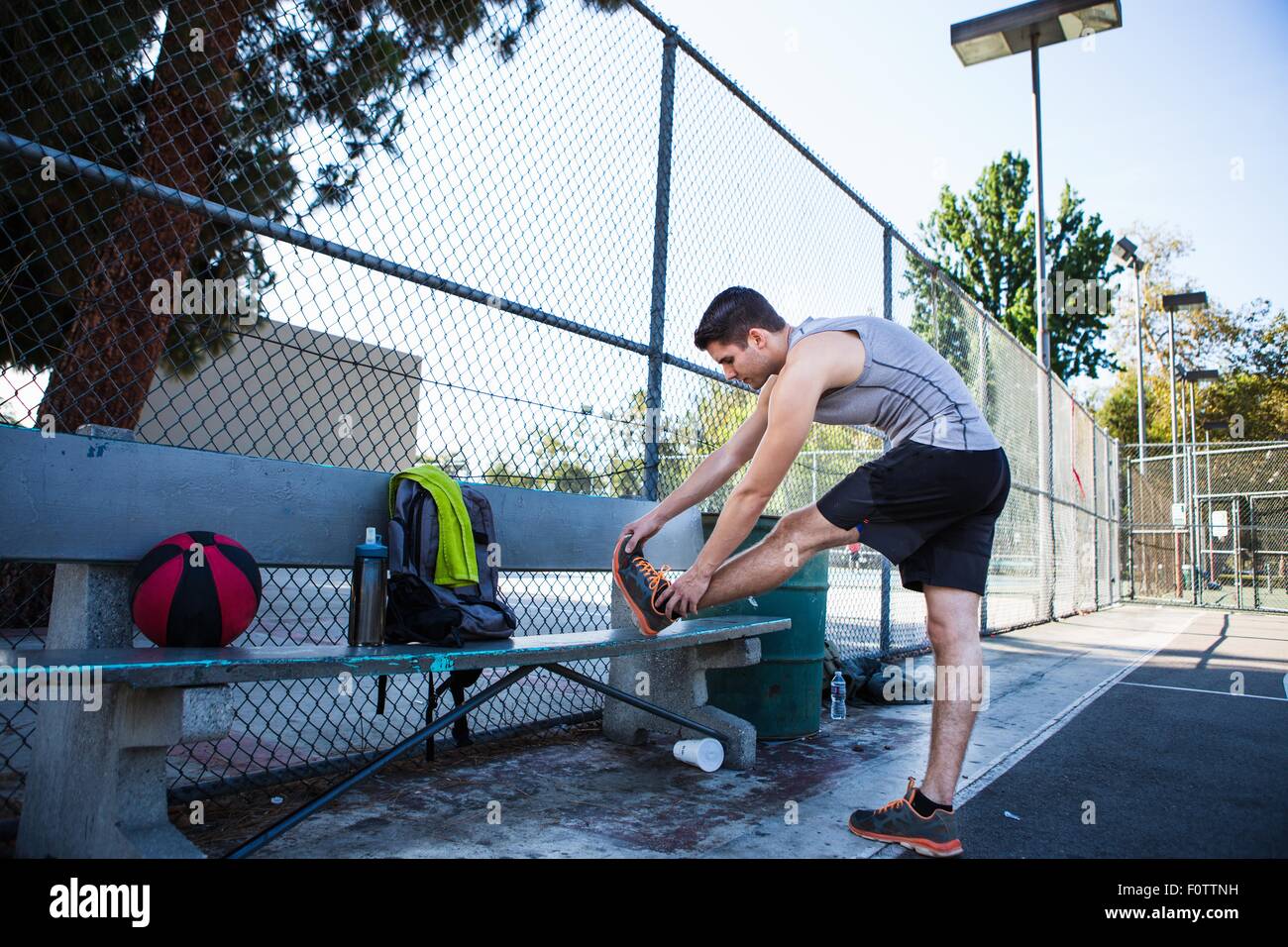 Young male basketball player stretching leg on basketball court Stock ...