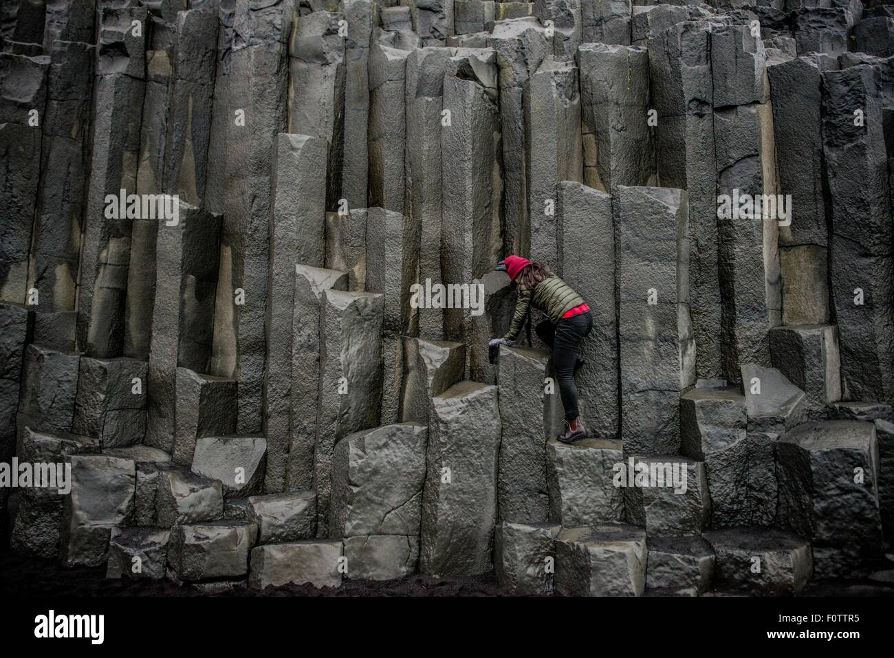 Female tourist climbing up rock formation, Reynisfjara, Iceland Stock ...