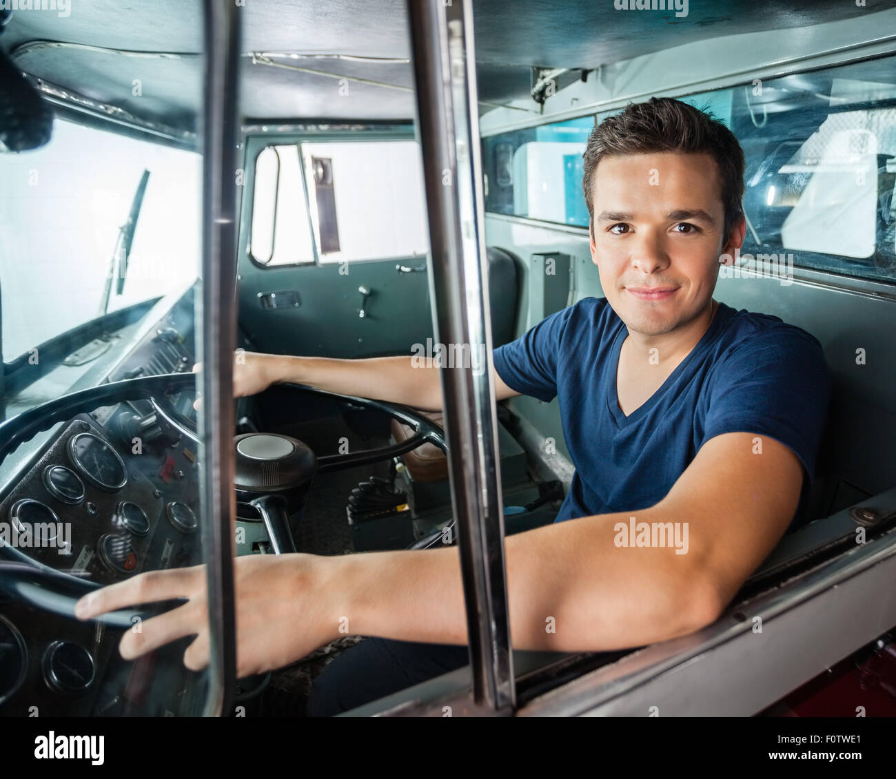 Portrait of confident male firefighter driving firetruck Stock Photo ...