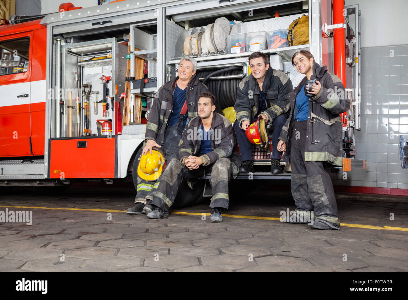 Team Of Thoughtful Firefighters By Firetruck Stock Photo - Alamy
