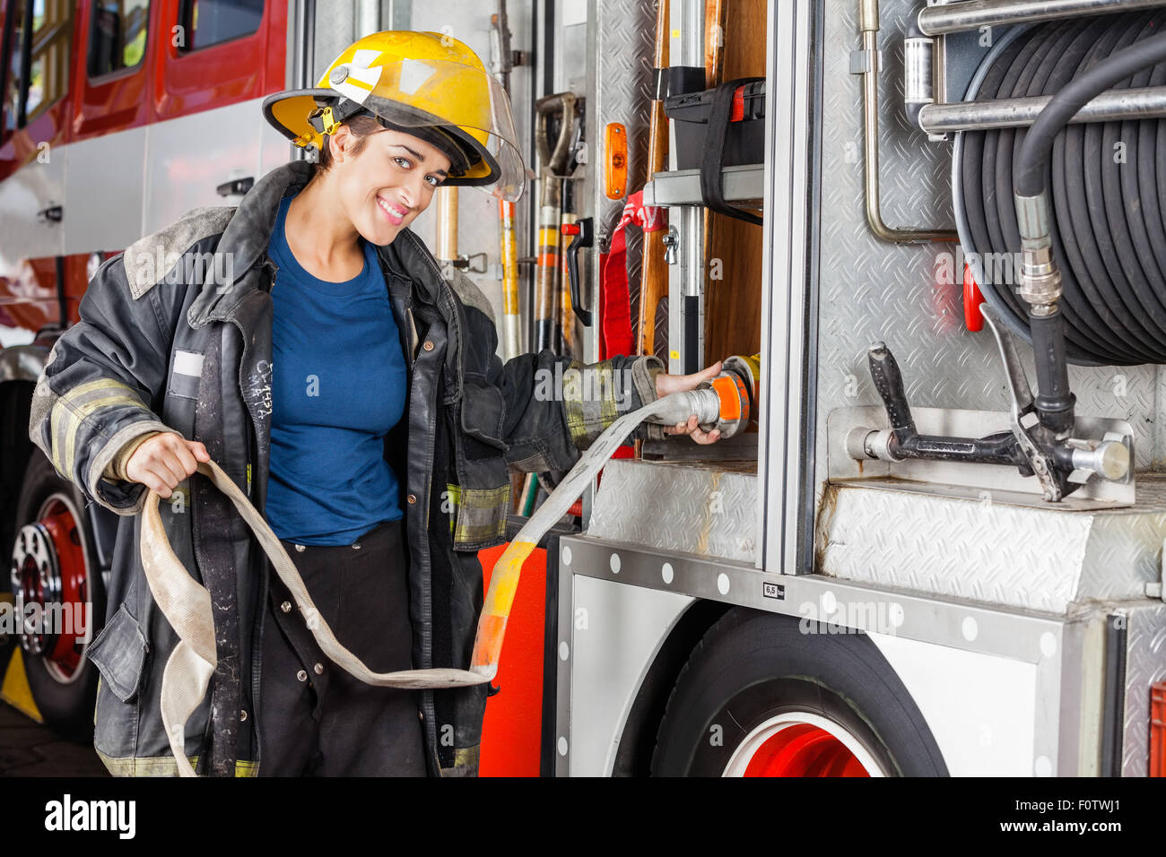 Portrait Of Happy Firefighter Adjusting Hose In Truck Stock Photo - Alamy