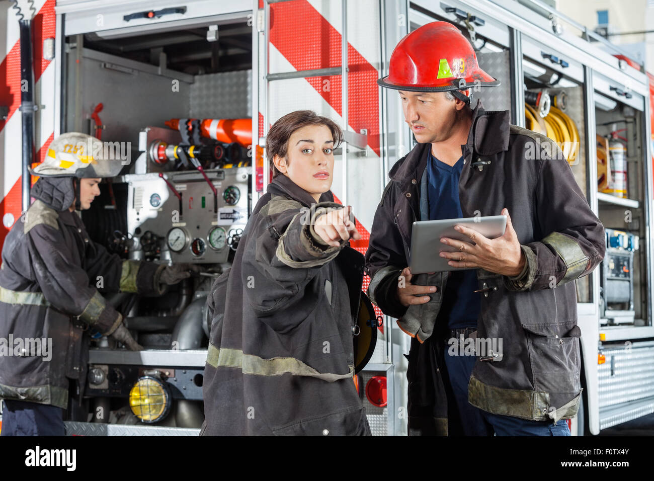 Firefighter Pointing While Colleague Holding Digital Tablet Stock Photo ...