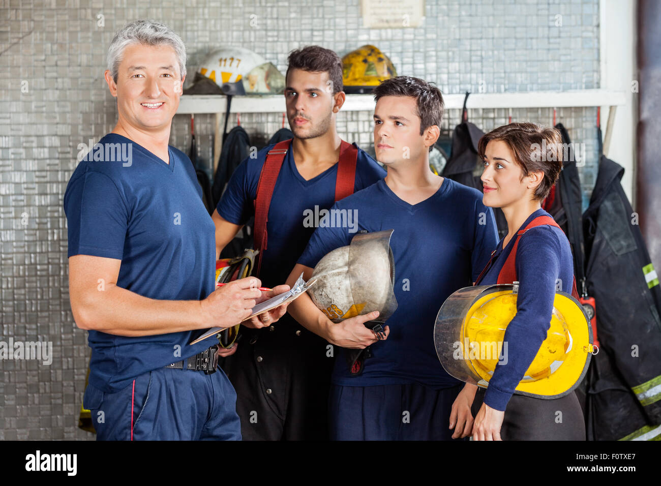 Happy Fireman Standing With Team At Fire Station Stock Photo - Alamy