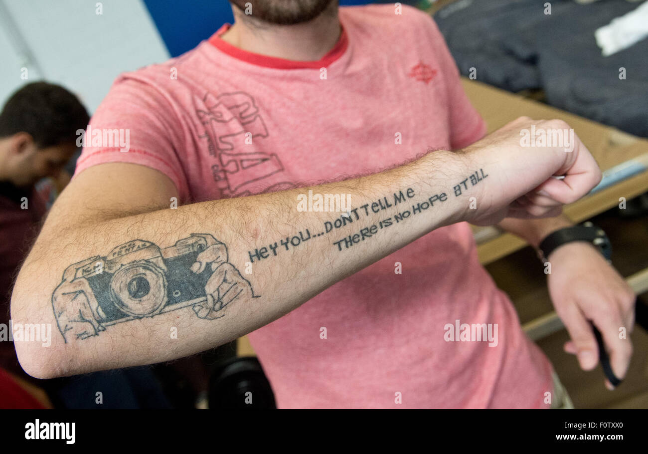 Stuttgart, Germany. 21st Aug, 2015. A Syrian refugee shows his tattoo ...