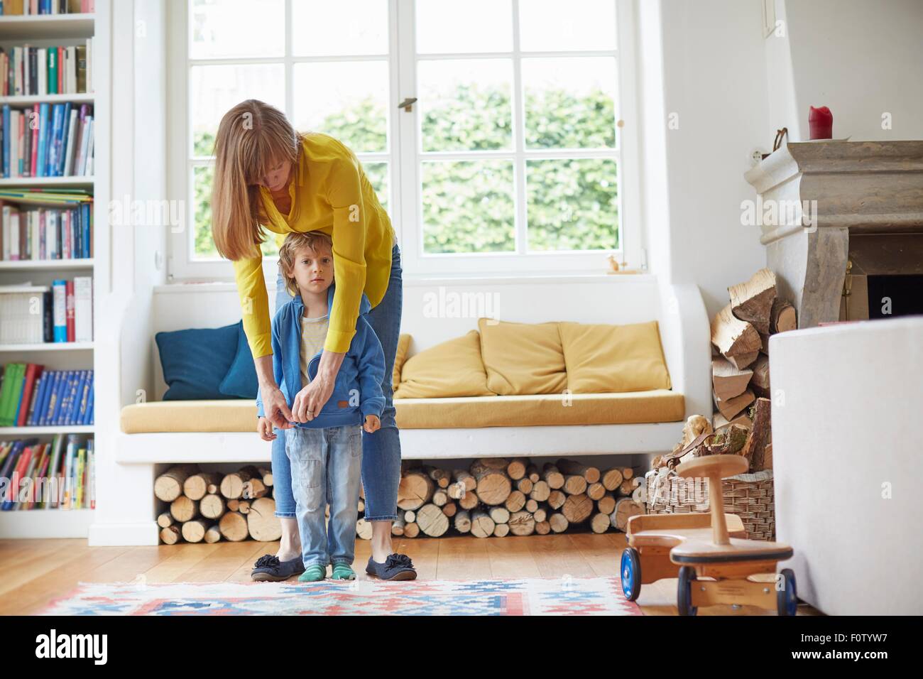 Mother helping son to get dressed Stock Photo - Alamy