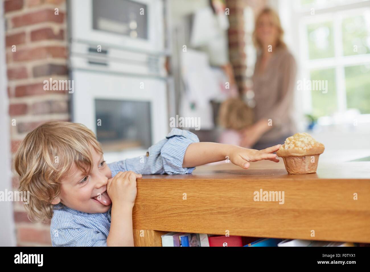 Young boy trying to reach muffin on kitchen counter Stock Photo - Alamy