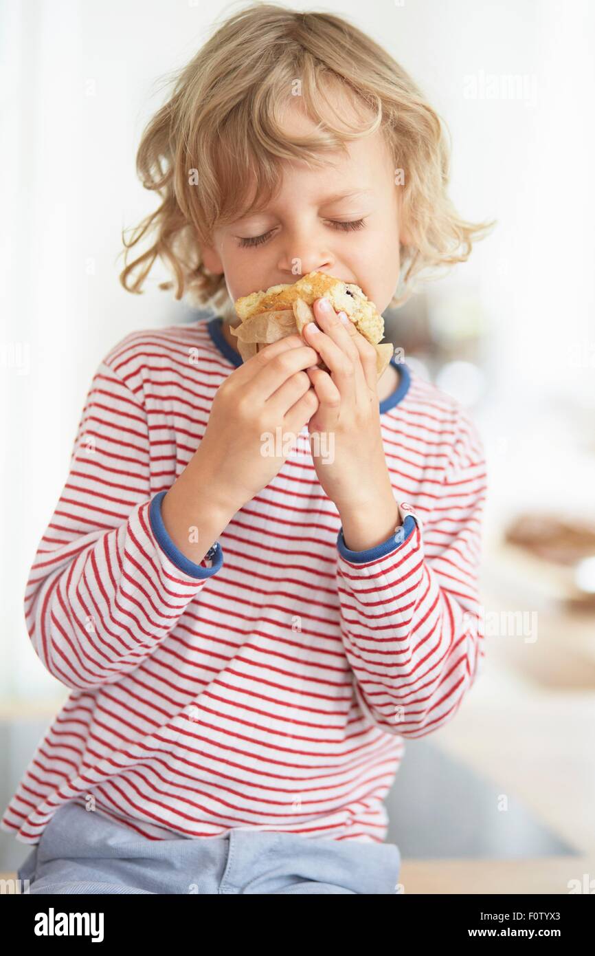Young boy eating muffin Stock Photo - Alamy