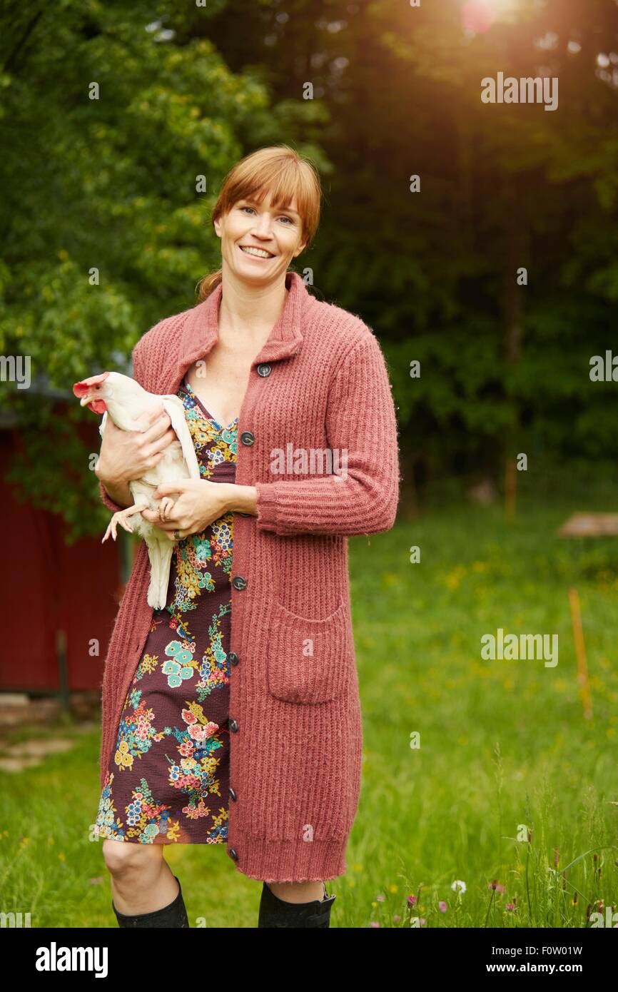 Portrait of woman in field holding hen Stock Photo - Alamy