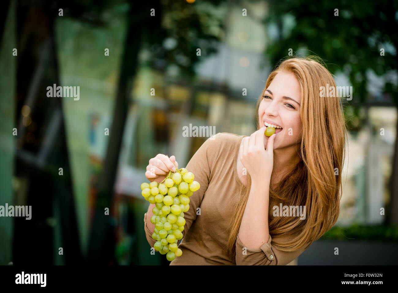 Young woman - teenage girl eating grapes outdoor in street Stock Photo ...