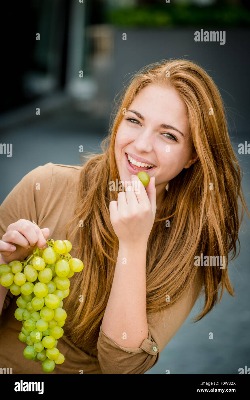Young woman - teenage girl eating grapes outdoor in street Stock Photo ...