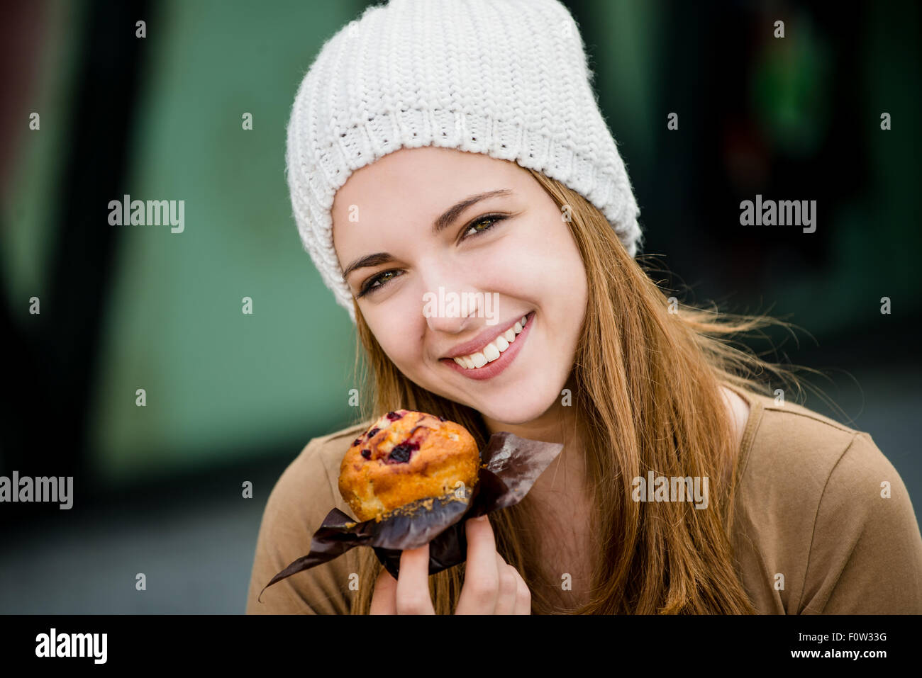 Young woman - teenager in cap eating muffin outdoor in street Stock ...
