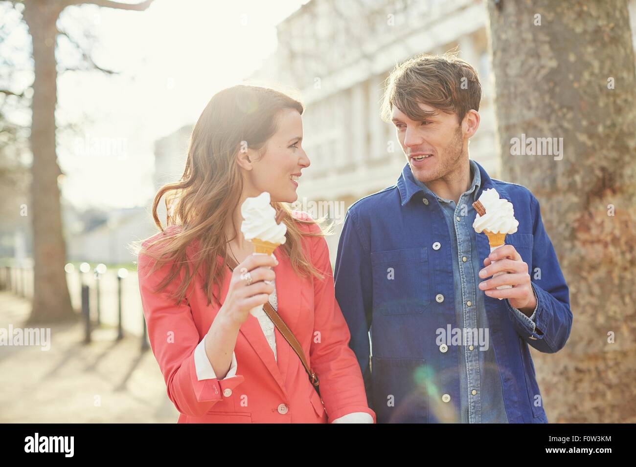 Couple eating ice cream cones whilst strolling along street, London, UK ...