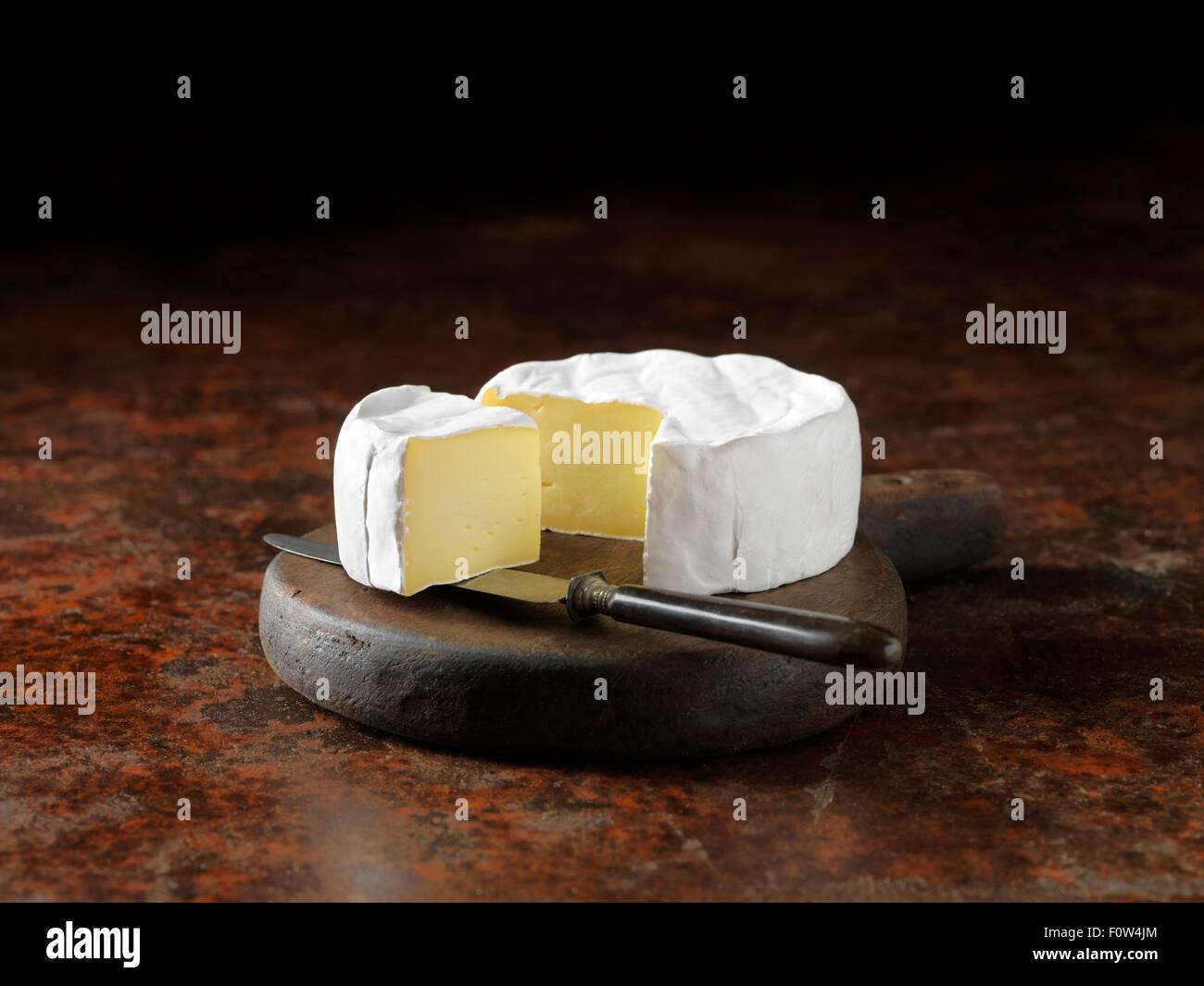 Cornish Brie on brown wooden round breadboard with knife Stock Photo ...