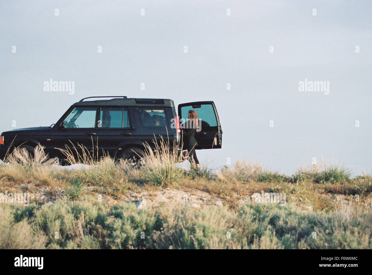 A woman standing by the open rear door of a 4x4 in open space Stock ...