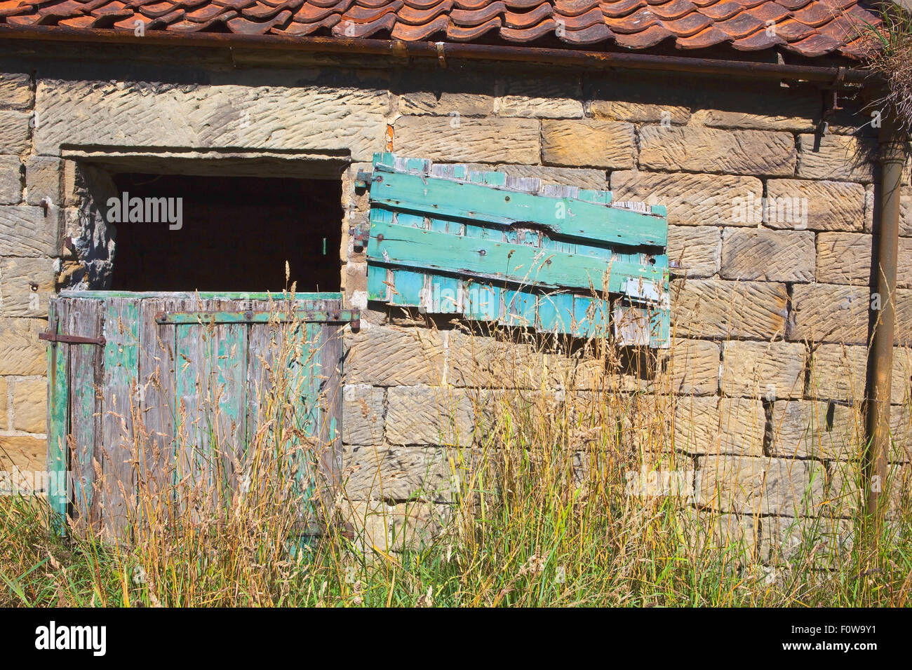 A dilapidated old stone barn with rusty guttering, pan-tile roof and ...