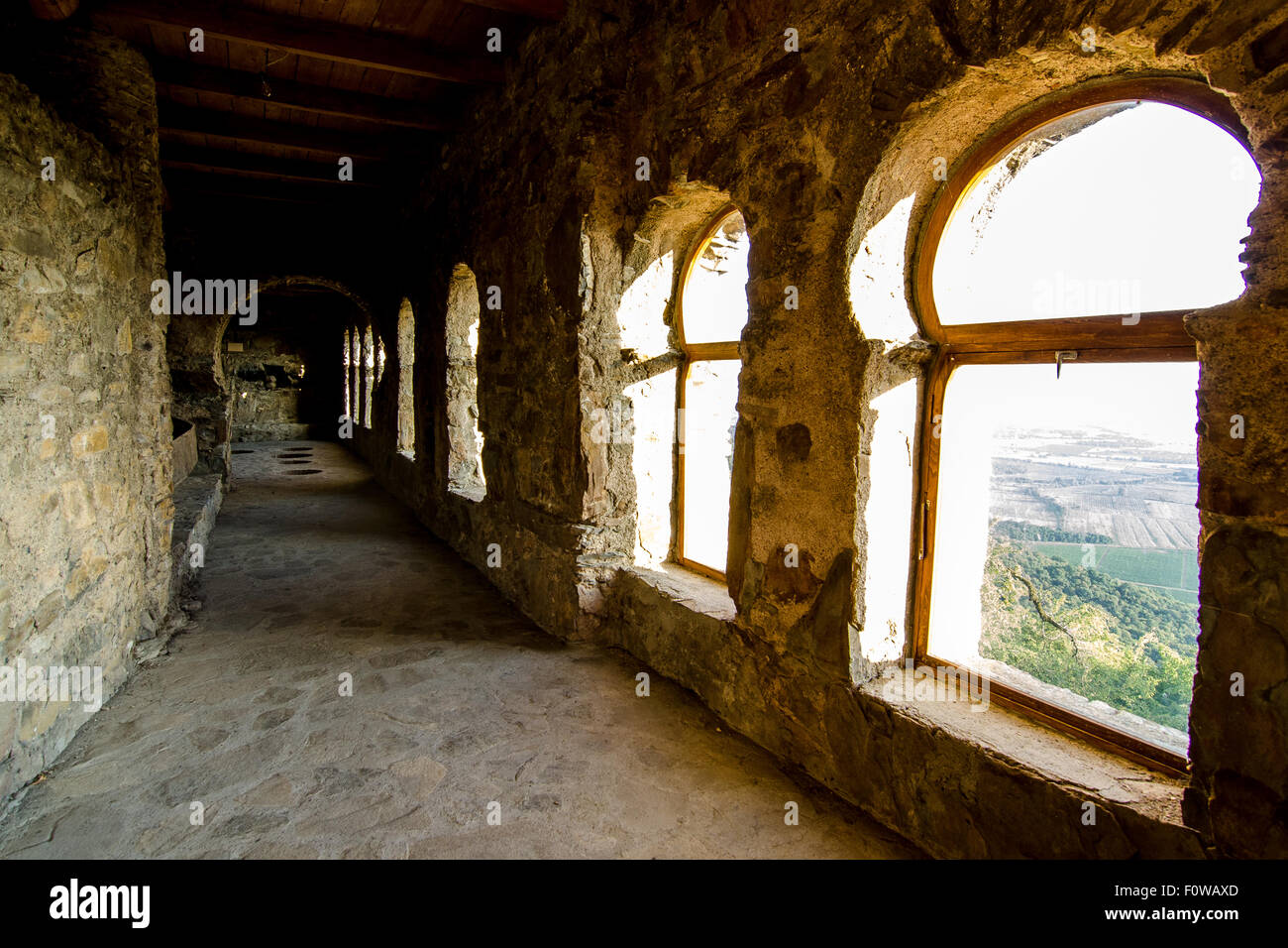 Stone corridor with arched windows overlooking countryside at golden ...