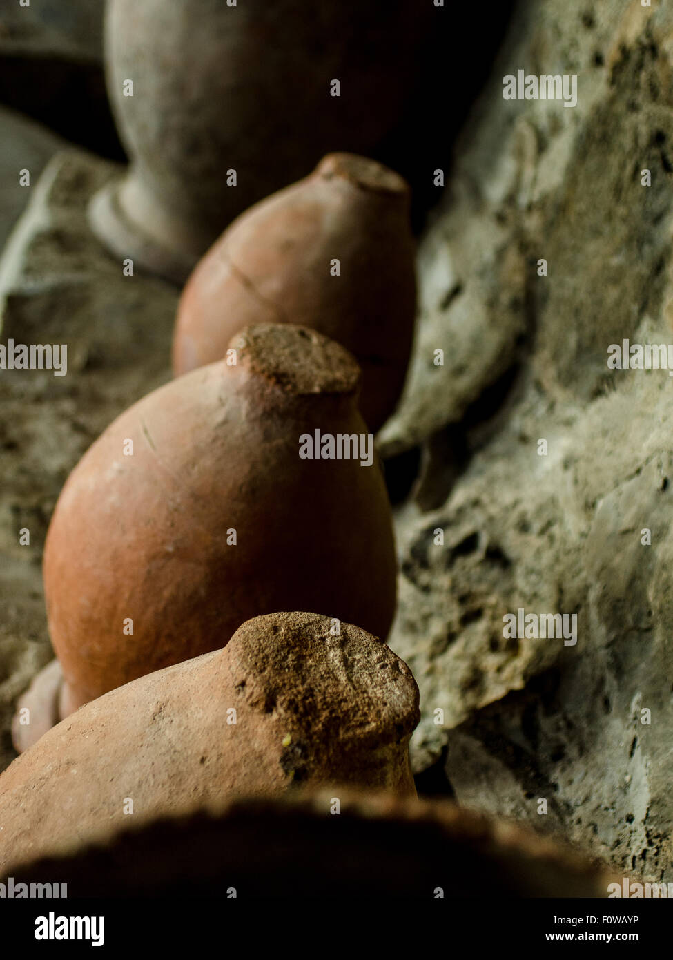 Ancient clay pots arranged neatly along a rocky surface in an ...