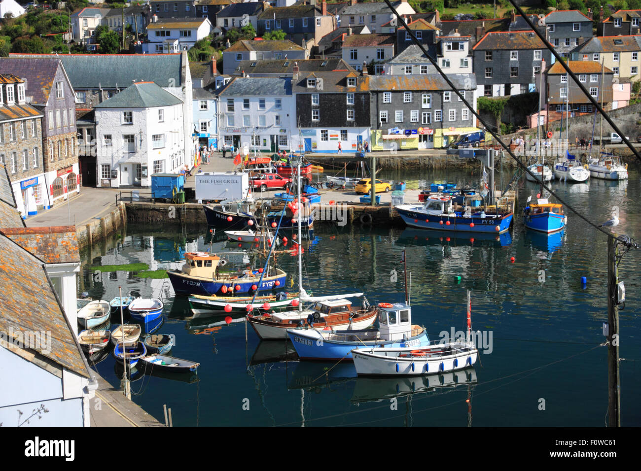 A Cornish fishing harbour with colourful cottages and boats at their ...