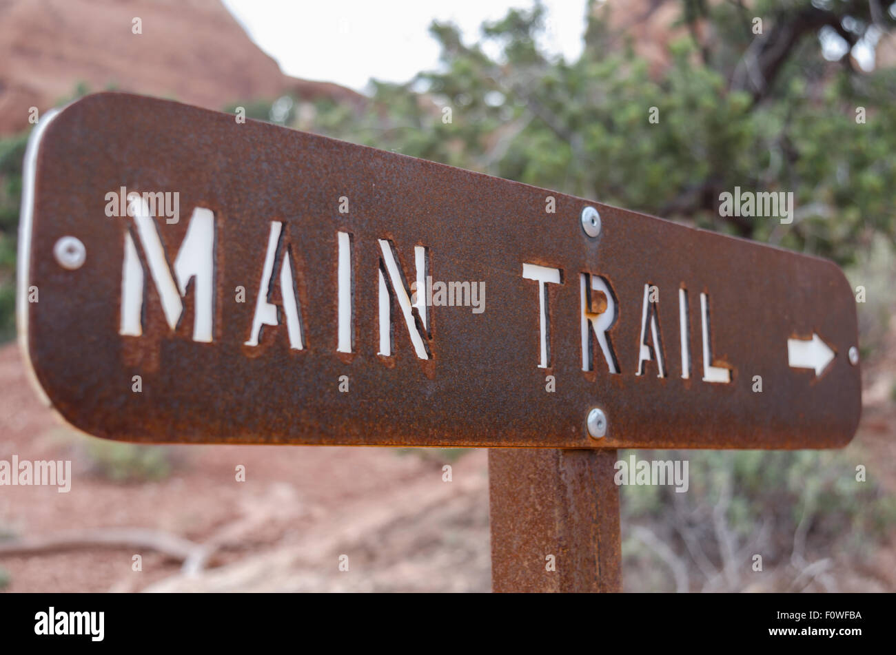 A brown metal sign directs hikers to the main trail in Arches National ...