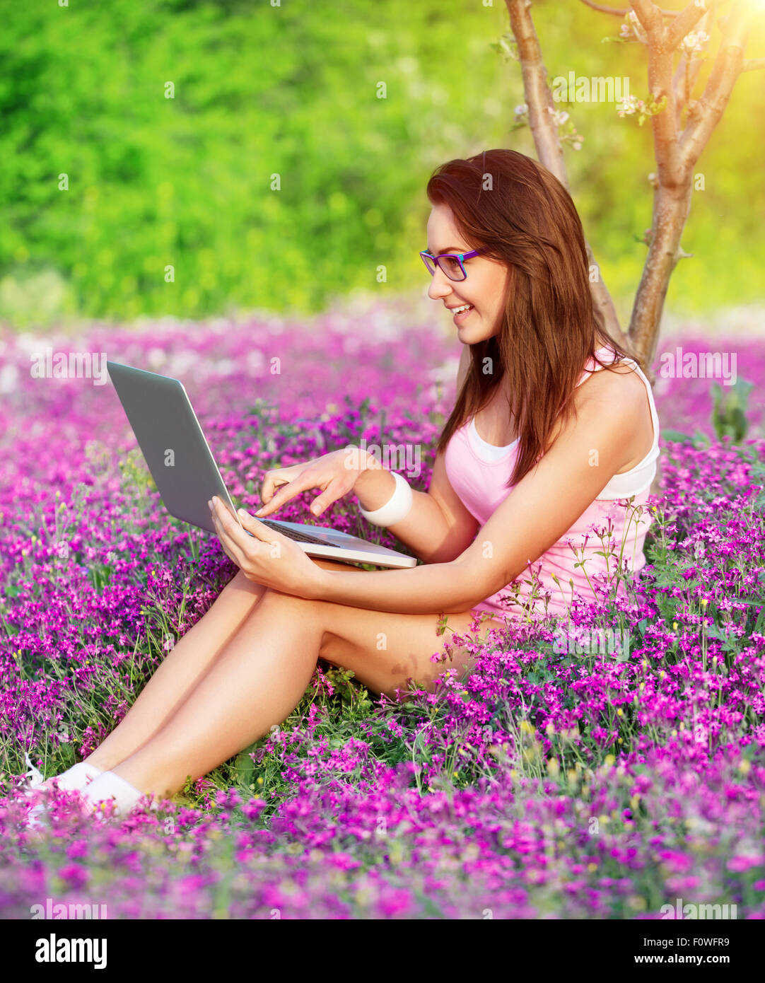 Student girl in the garden, working on laptop in beautiful fresh garden ...