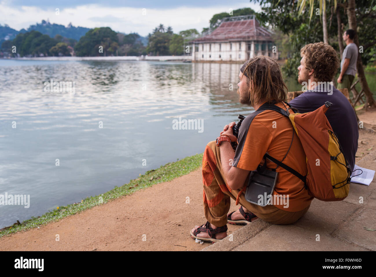 Young Man Traveler with backpack reading book and writing notes outdoor ...