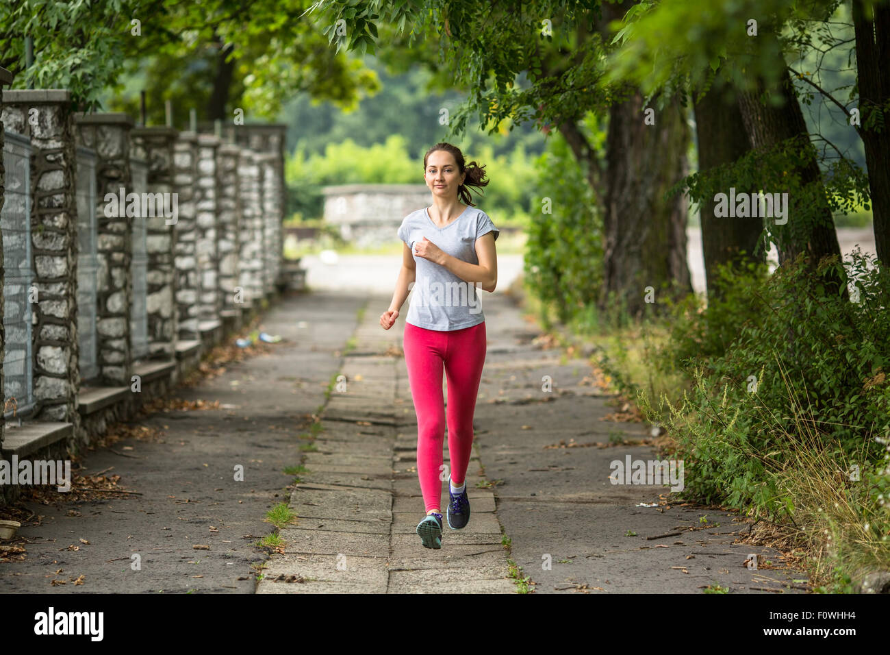 Young woman running on the track through the summer park. Training ...