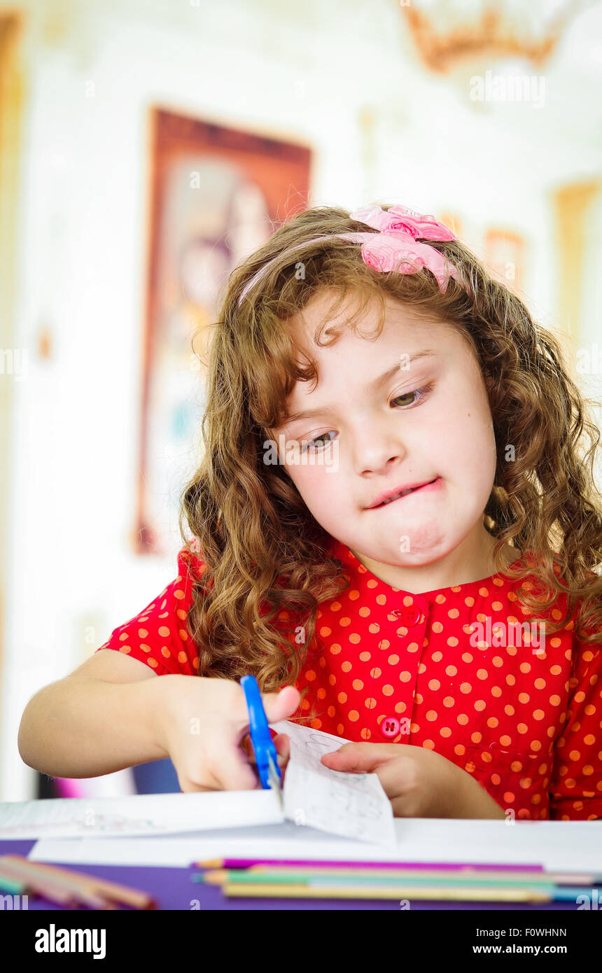 Cute little girl practicing cutting with scissors Stock Photo - Alamy