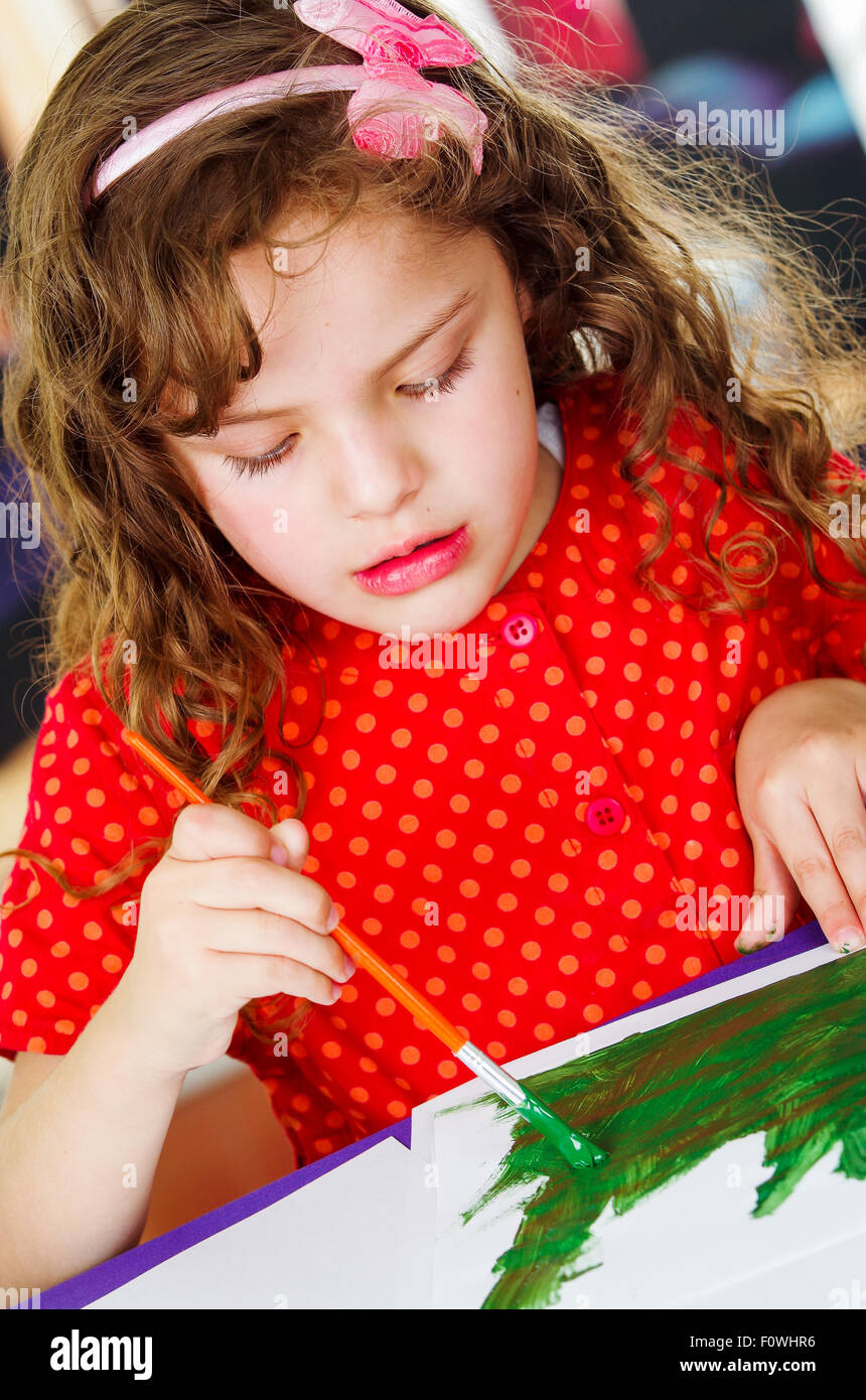 Sweet girl holding paint brush painting Stock Photo - Alamy