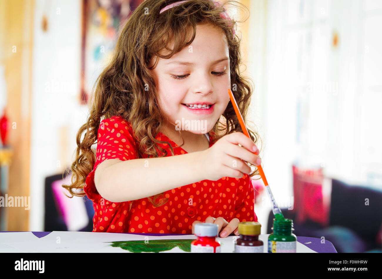 Happy little artistic girl painting Stock Photo - Alamy
