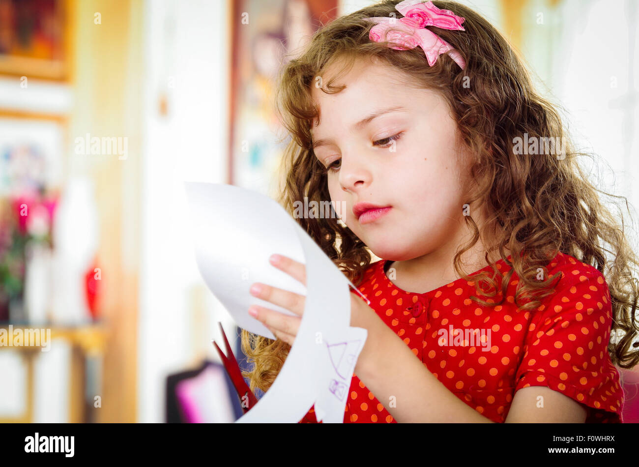 Cute girl cutting paper with scissors Stock Photo - Alamy