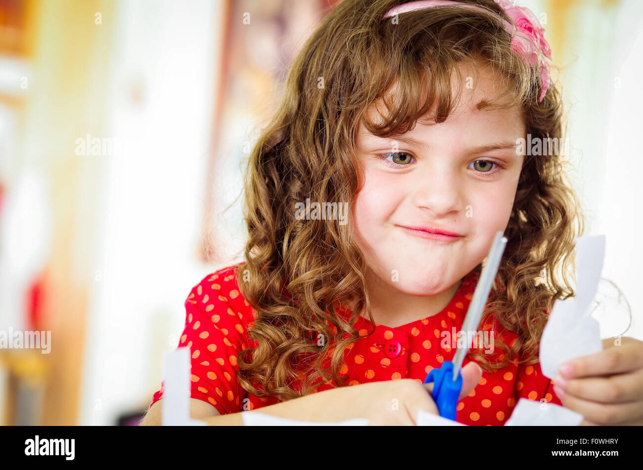 Cute girl cutting paper with scissors Stock Photo - Alamy