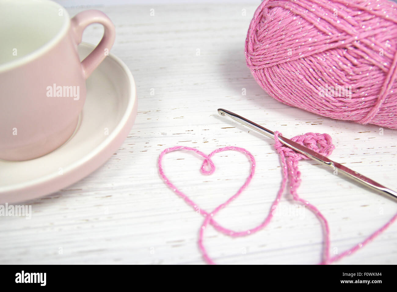 pink crochet background with yarn heart and coffee cup and crochet hook ...