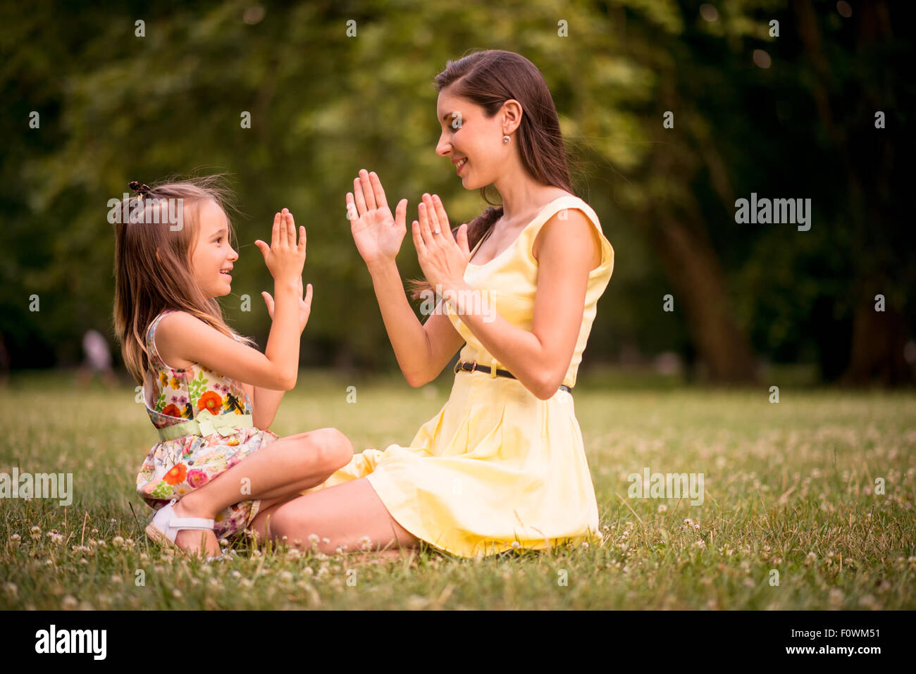 Clapping hands - mother playing with her daughter outdoor in nature ...