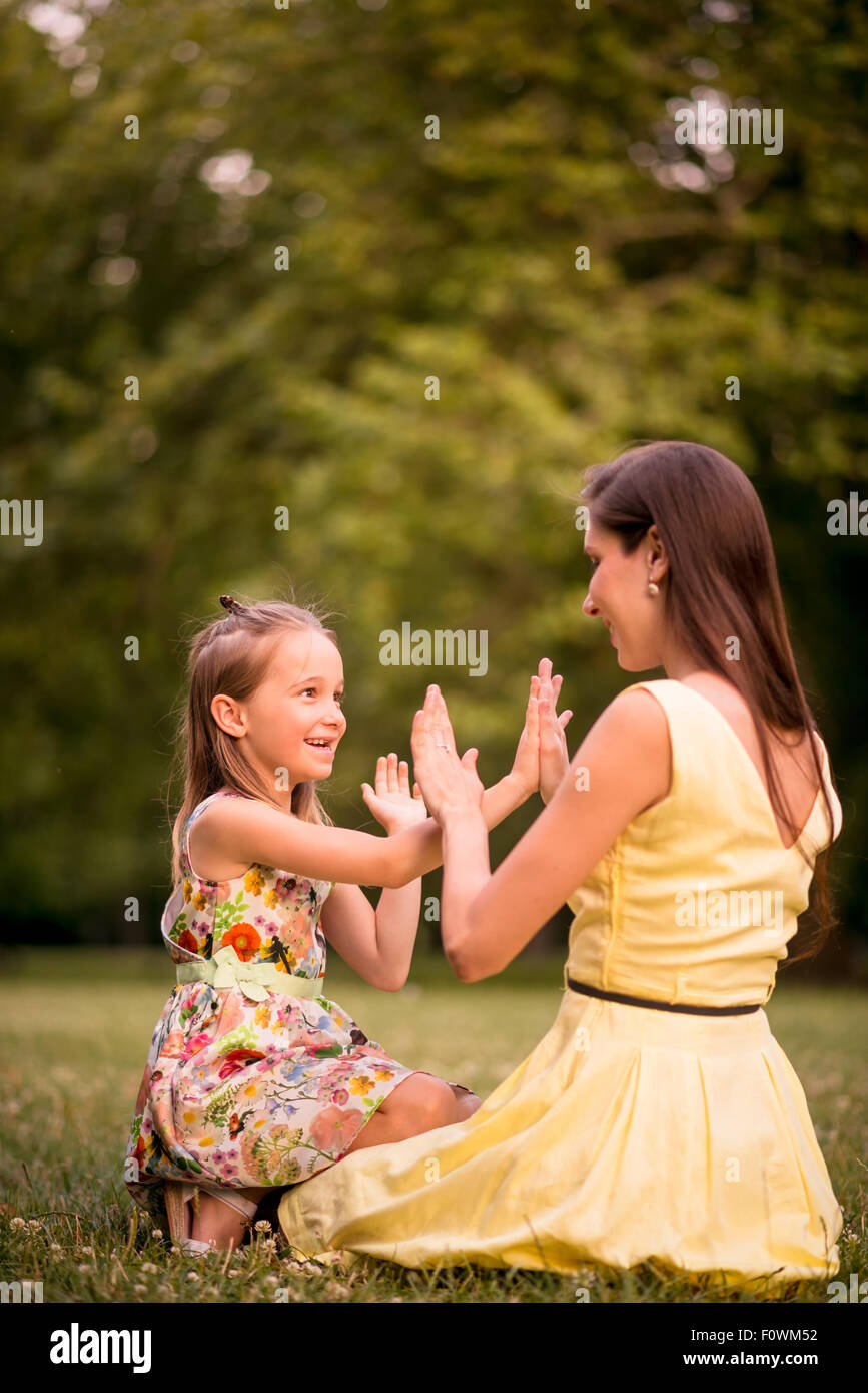 Clapping hands - mother playing with her daughter outdoor in nature ...