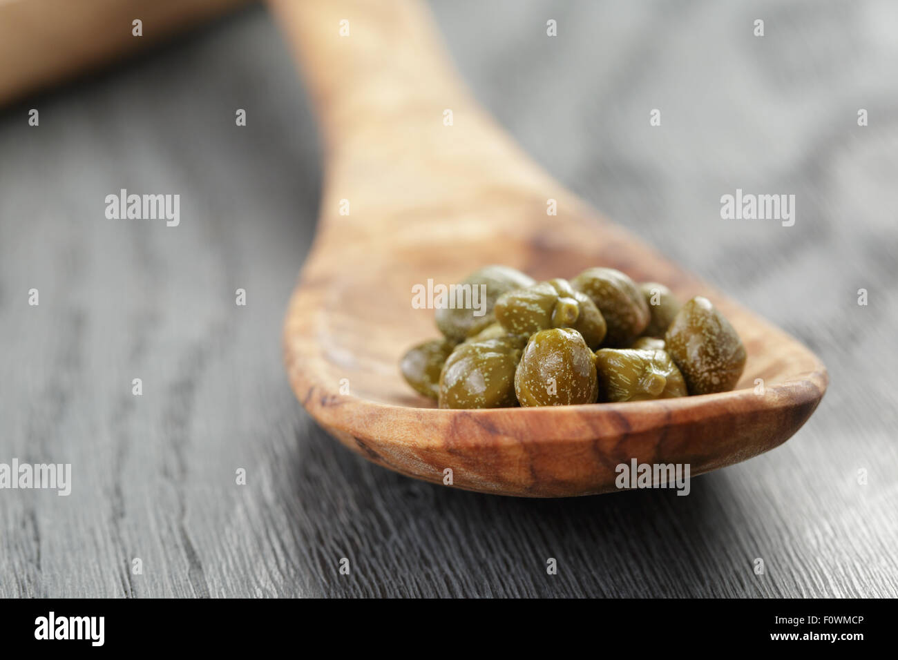 marinated capers in wood spoon on table Stock Photo - Alamy