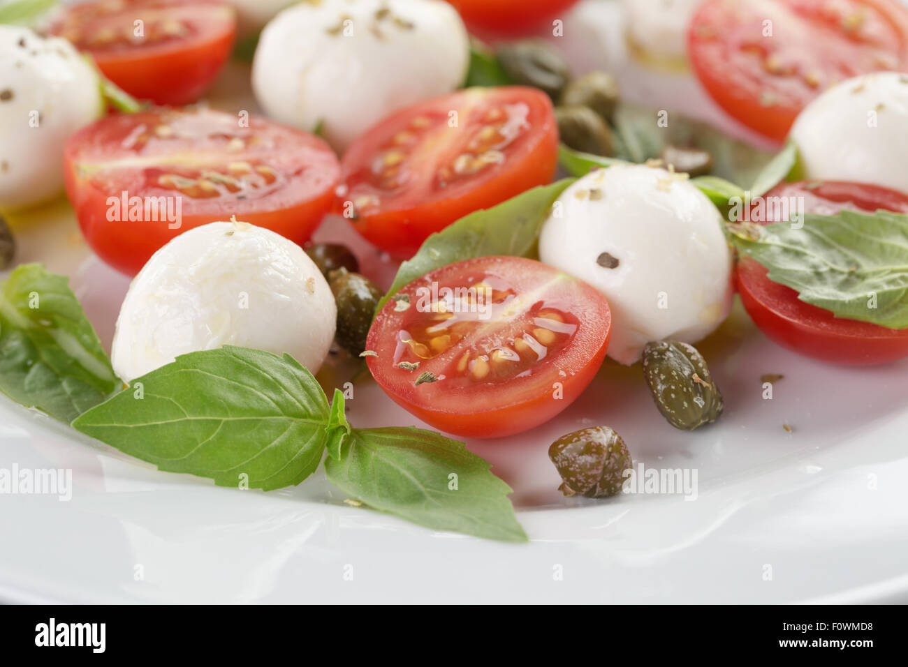 caprese salad with mini mozzarella balls, tomatoes and capers Stock ...